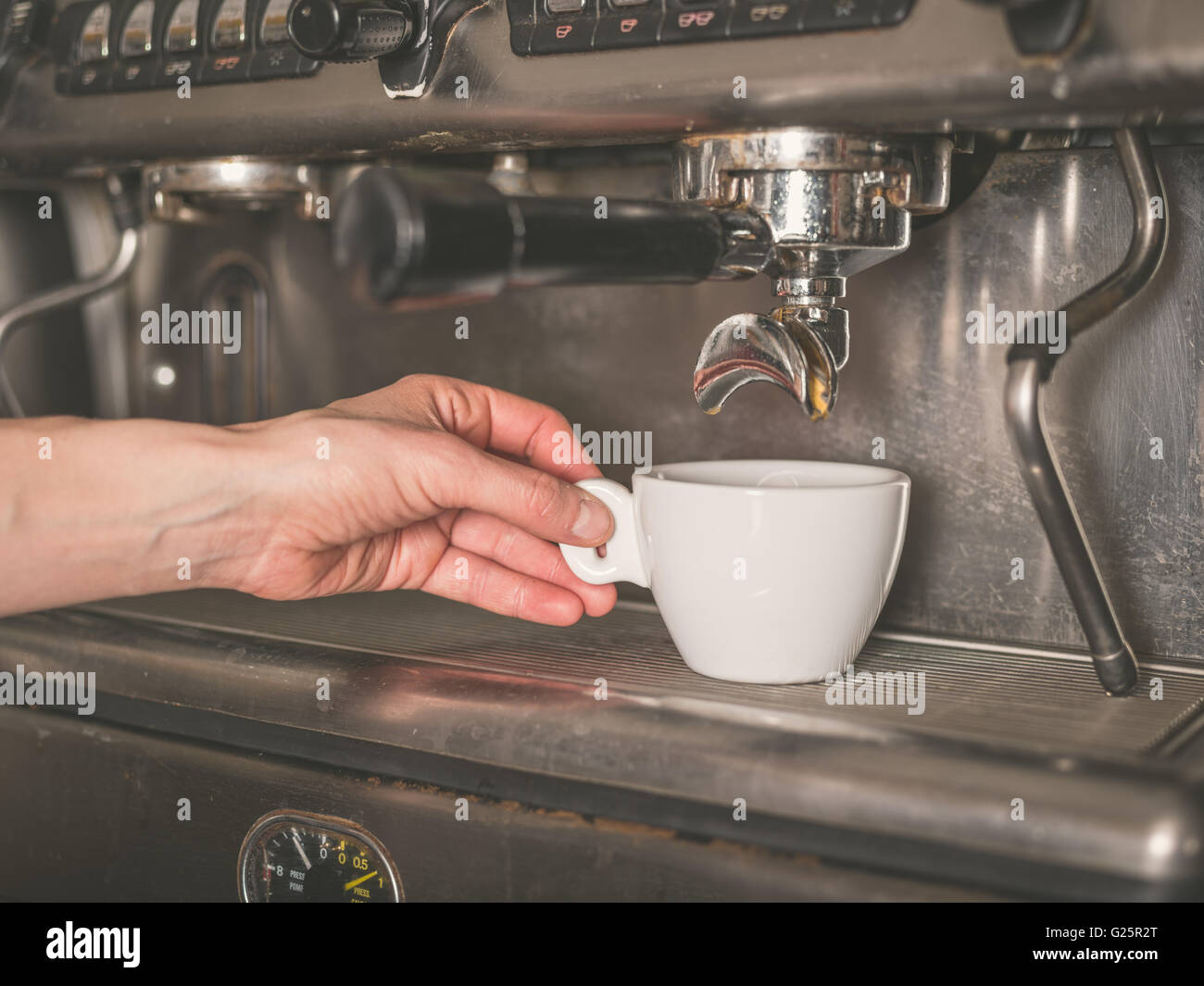 The hand of a young woman is operating a professional coffee machine ...
