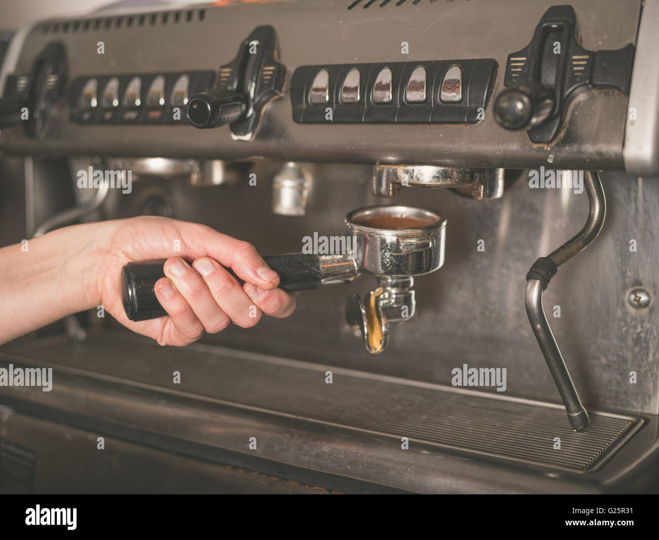 The hand of a young woman is operating a professional coffee machine ...