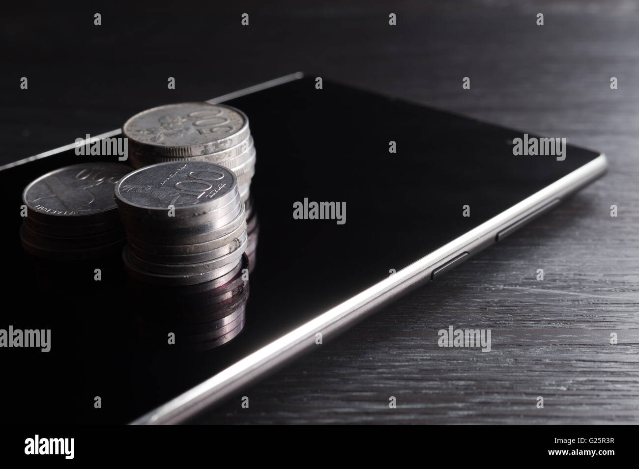 Stack of rupiah coin on smartphone showing it relation. Like business ...