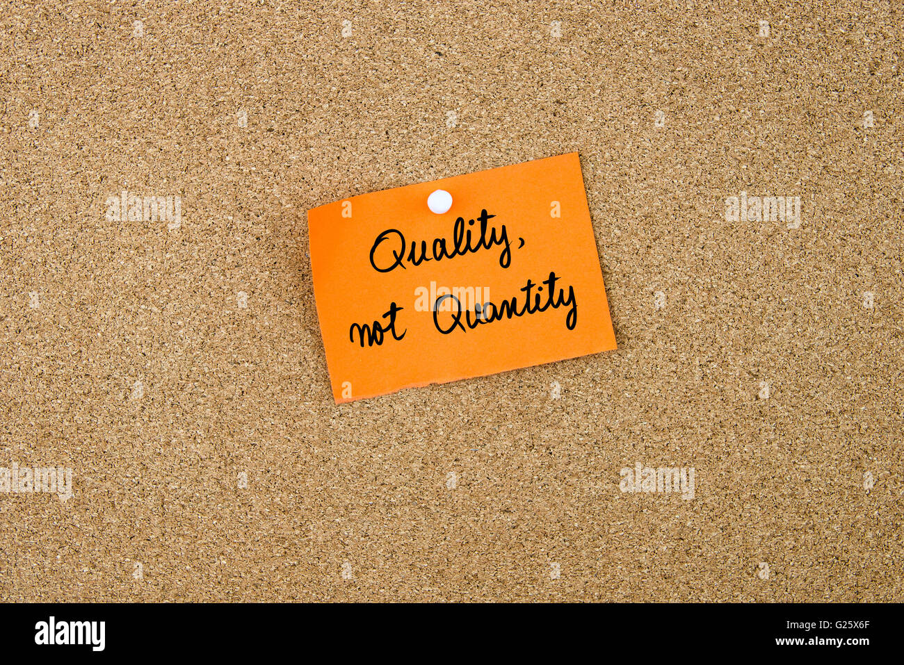 QUALITY, not QUANTITY written on orange paper note pinned on cork board ...