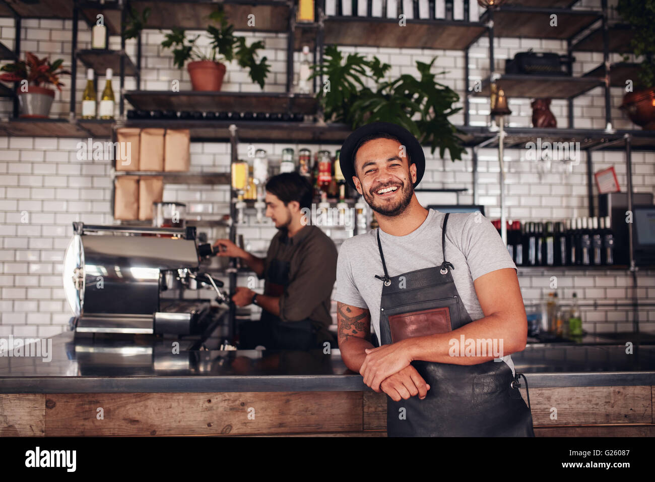 Coffee shop worker smiling to camera, standing at the counter. Happy ...