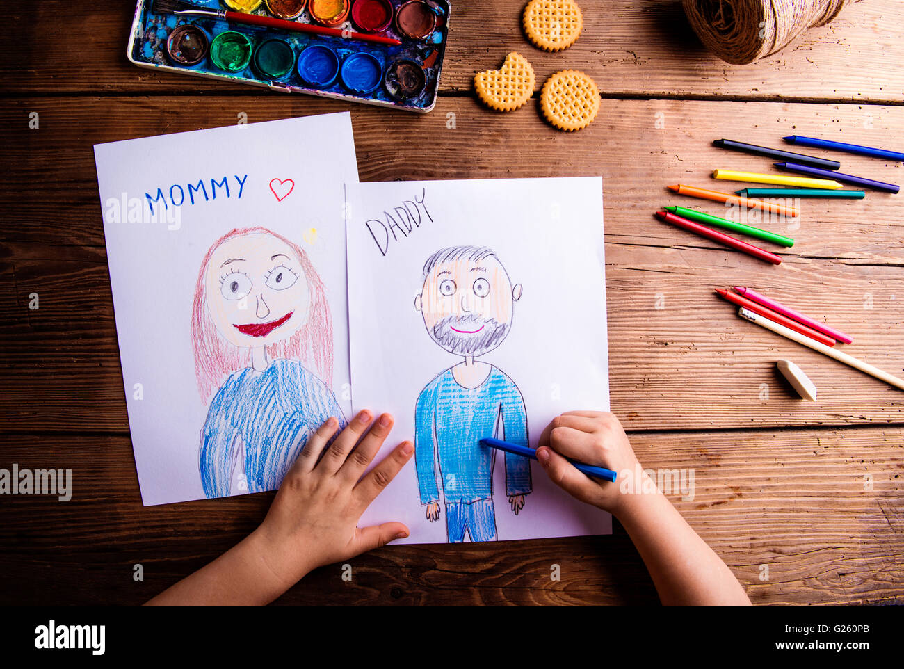 Unrecognizable girl drawing pictures of her mother and father Stock ...