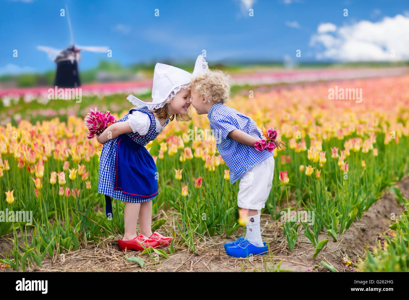 Happy Dutch children playing in blooming tulip flowers field. Boy and ...