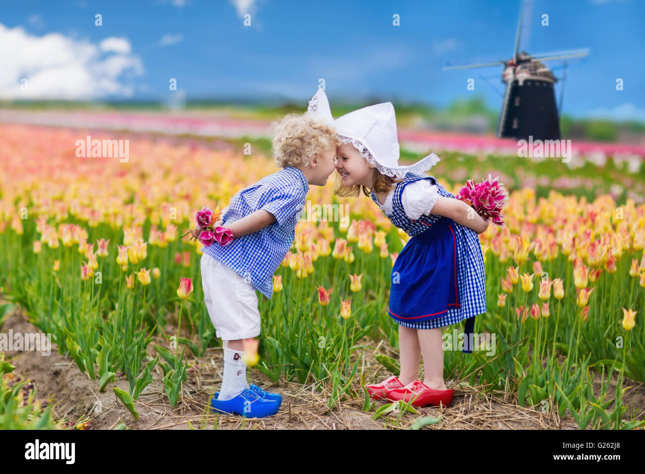 Happy Dutch children playing in blooming tulip flowers field. Boy and ...