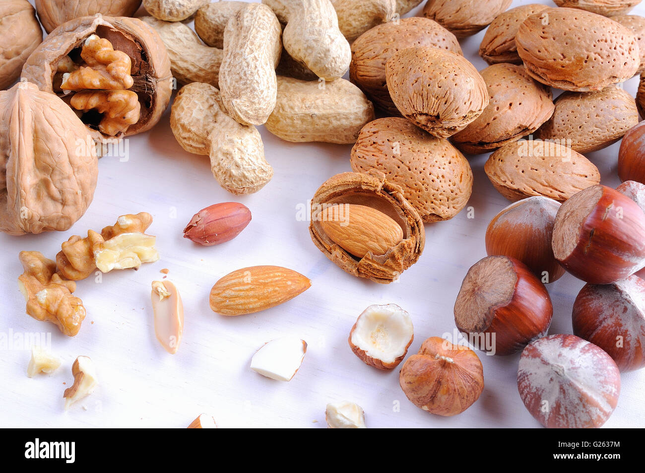 Group tasty nuts in shell and shelled on a white wooden table top view ...