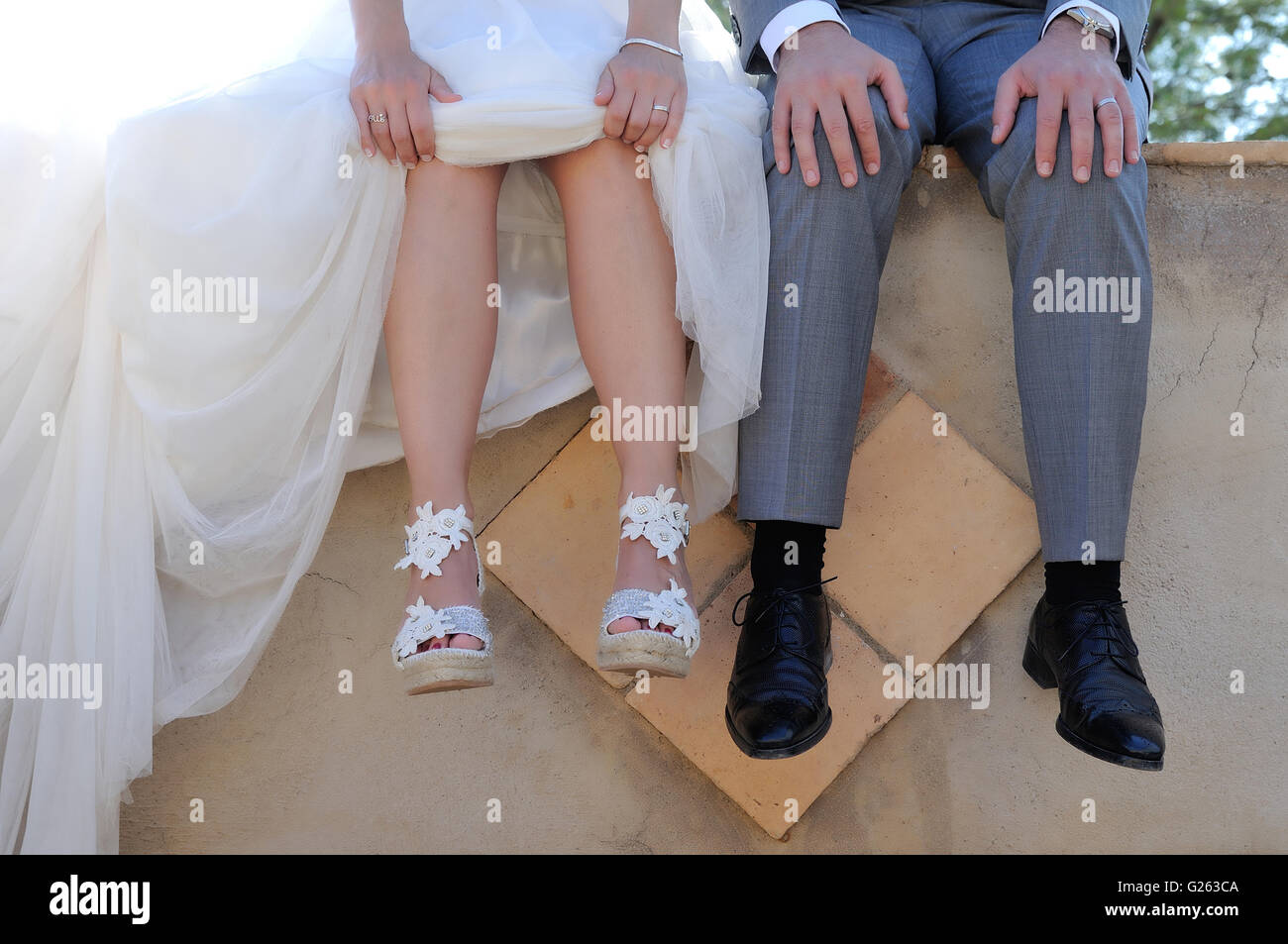 feet of bride and groom sitting on a concrete wall outdoor Stock Photo ...