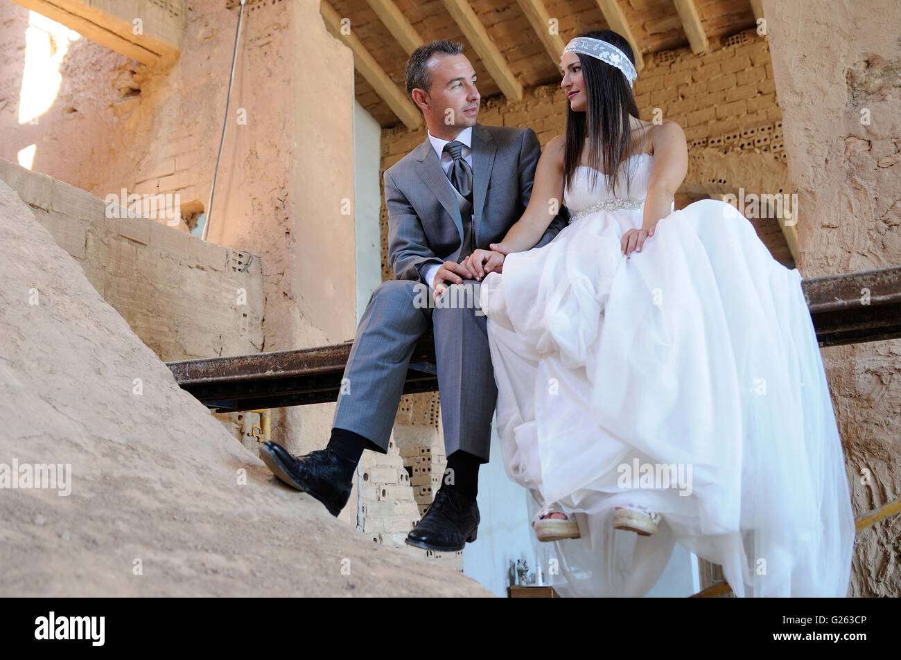 Groom and bride sitting on a scaffolding in a warehouse in ruins Stock ...