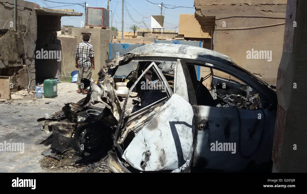 Fallujah, Iraq. 24th May, 2016. A man stands by a damaged car which was ...