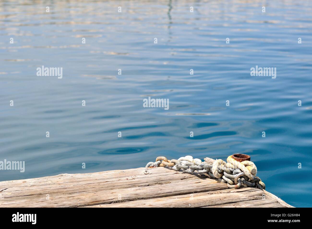 Metal ship chains and mooring bollard on wooden pier. Podgora, Croatia ...