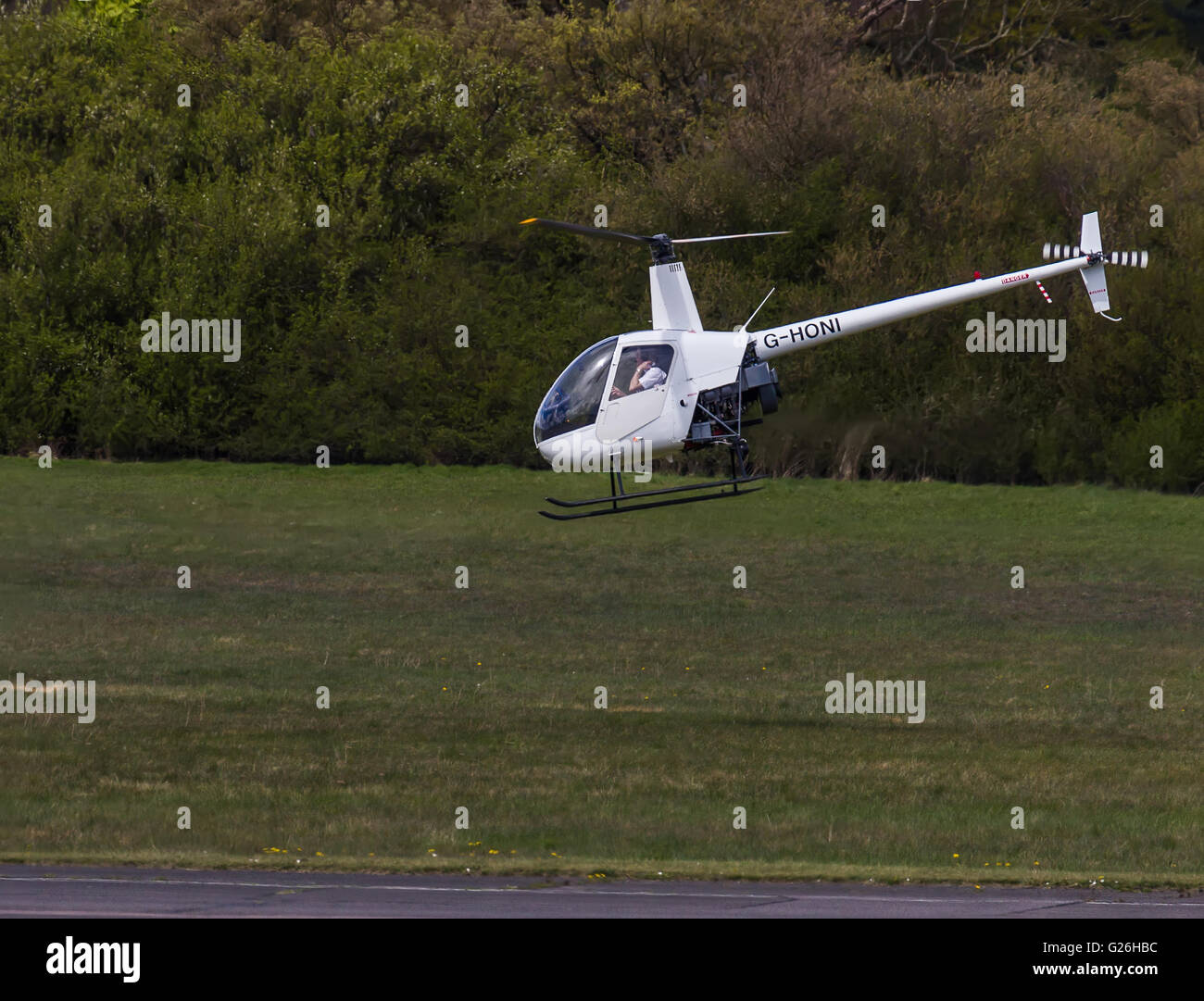 A two-seater Robinson R22 helicopter, G-HONI, flying low, very near the ...