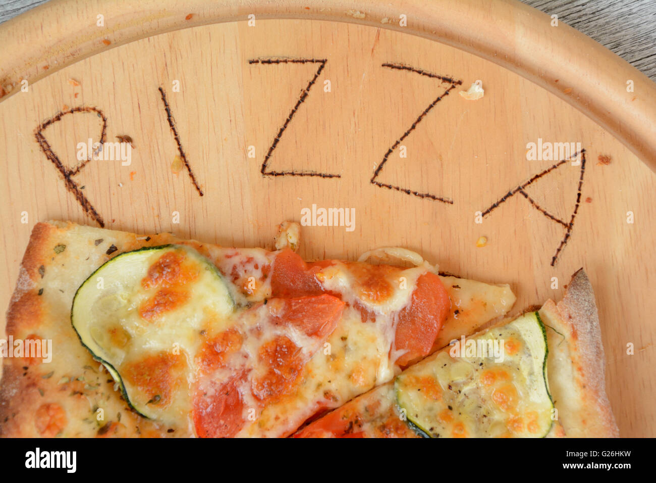 Pizza and pizza word scorched on round wooden plate Stock Photo - Alamy