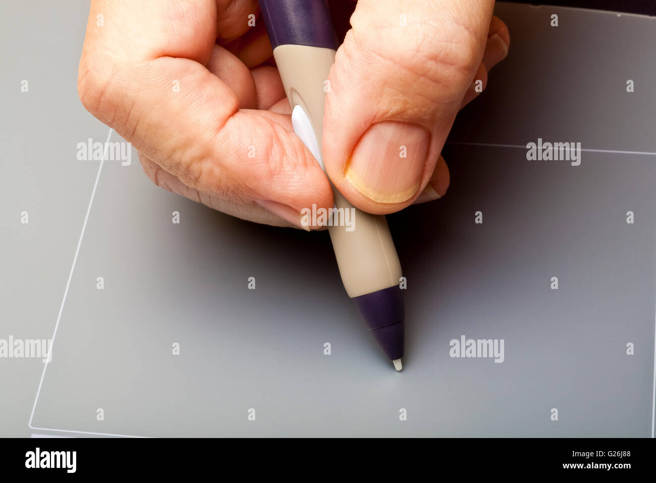 older man's hand holding stylus on graphics tabet Stock Photo - Alamy