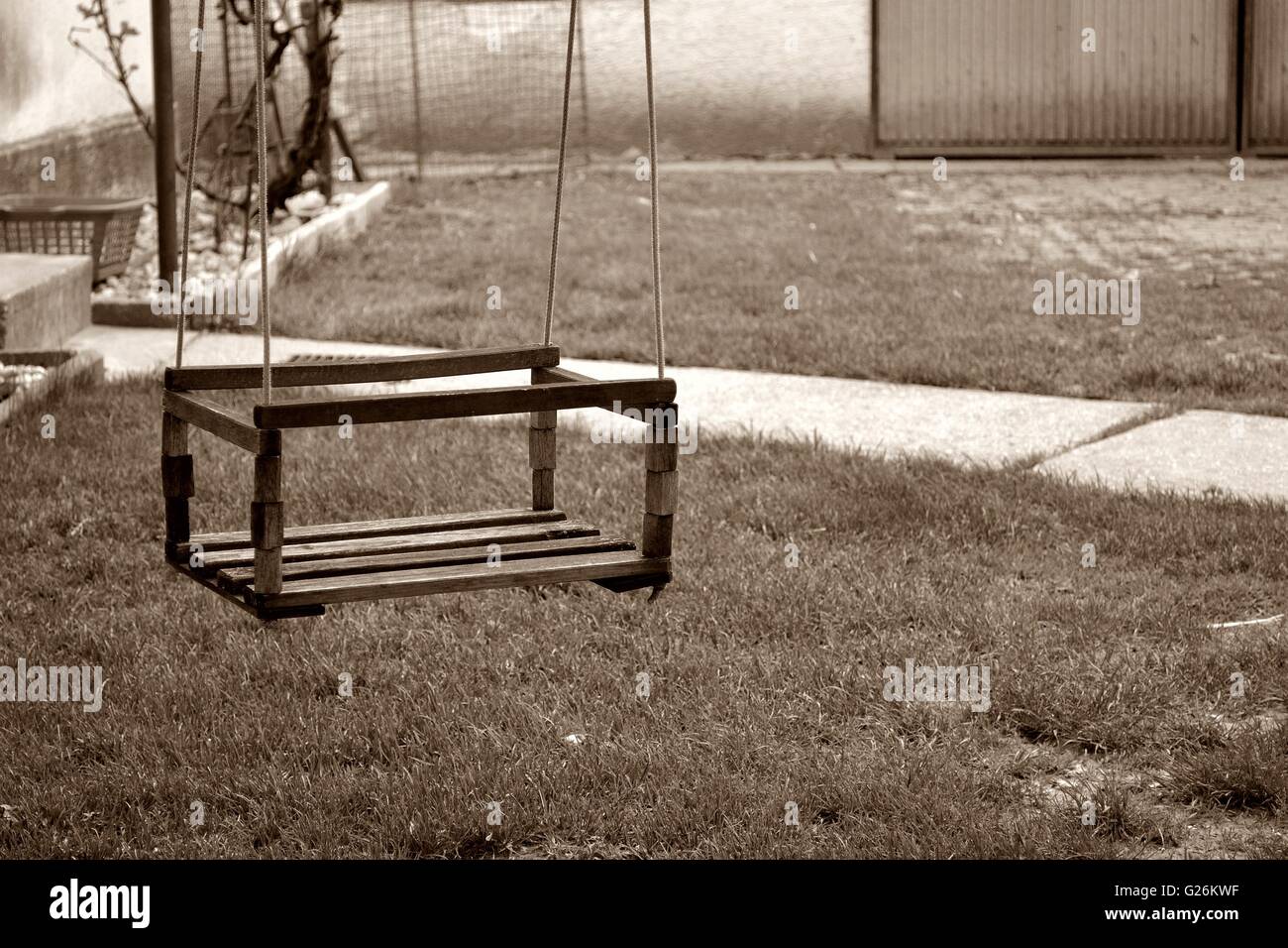 Empty swing hanging in yard Stock Photo - Alamy
