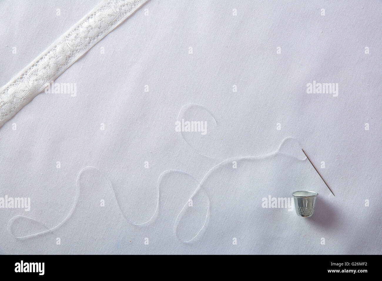 Background sewing needle threaded with white thread thimble and lace ...