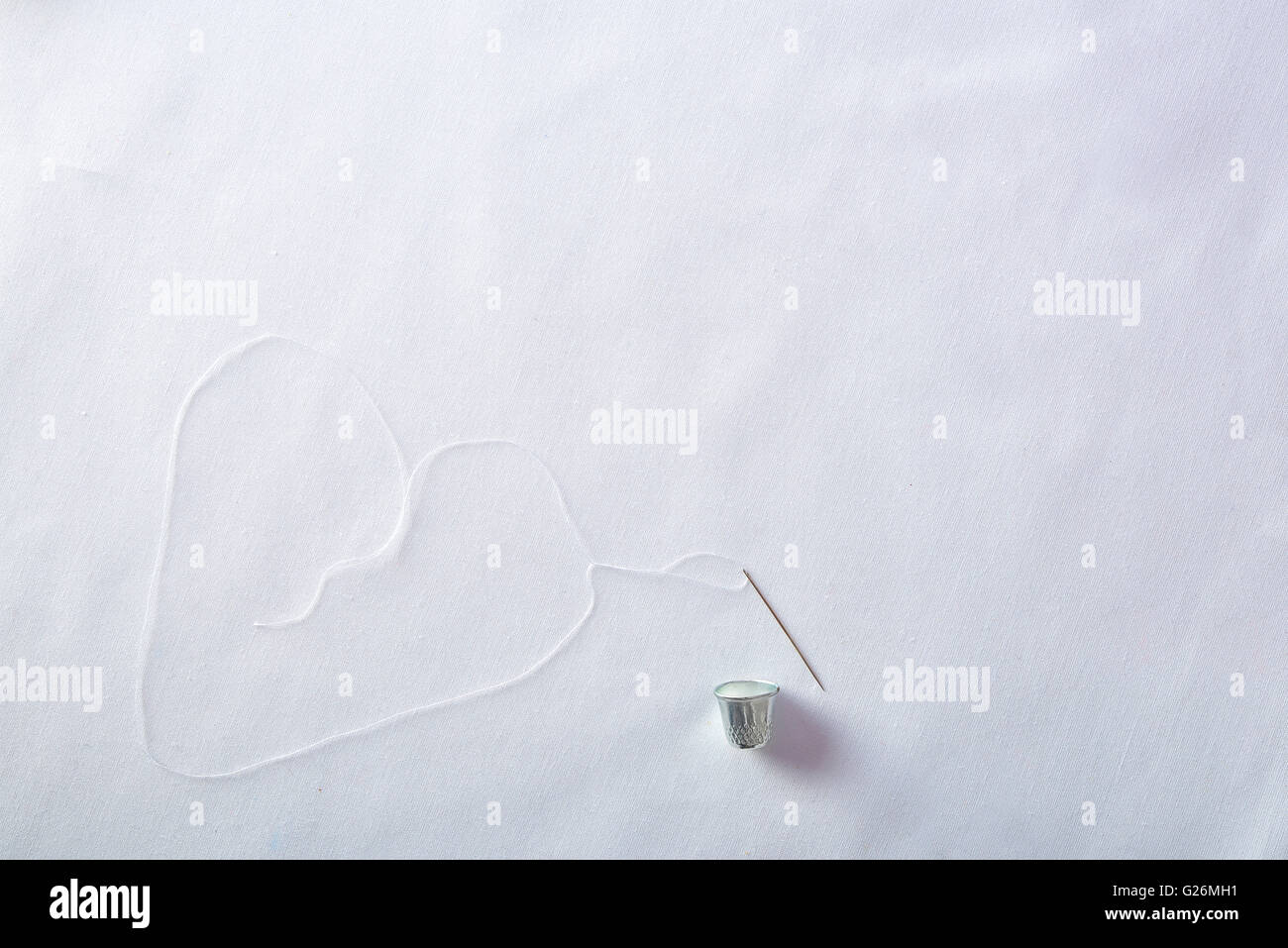 Threading needle thread forming a heart background on white cloth ...