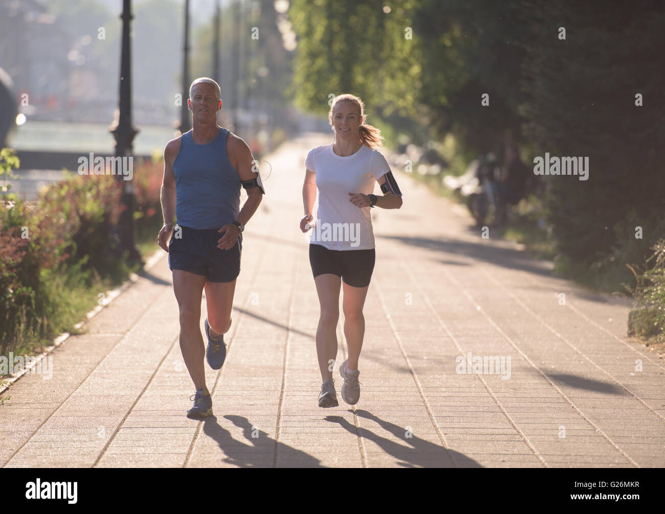 jogging couple warming up and stretching before morning running ...