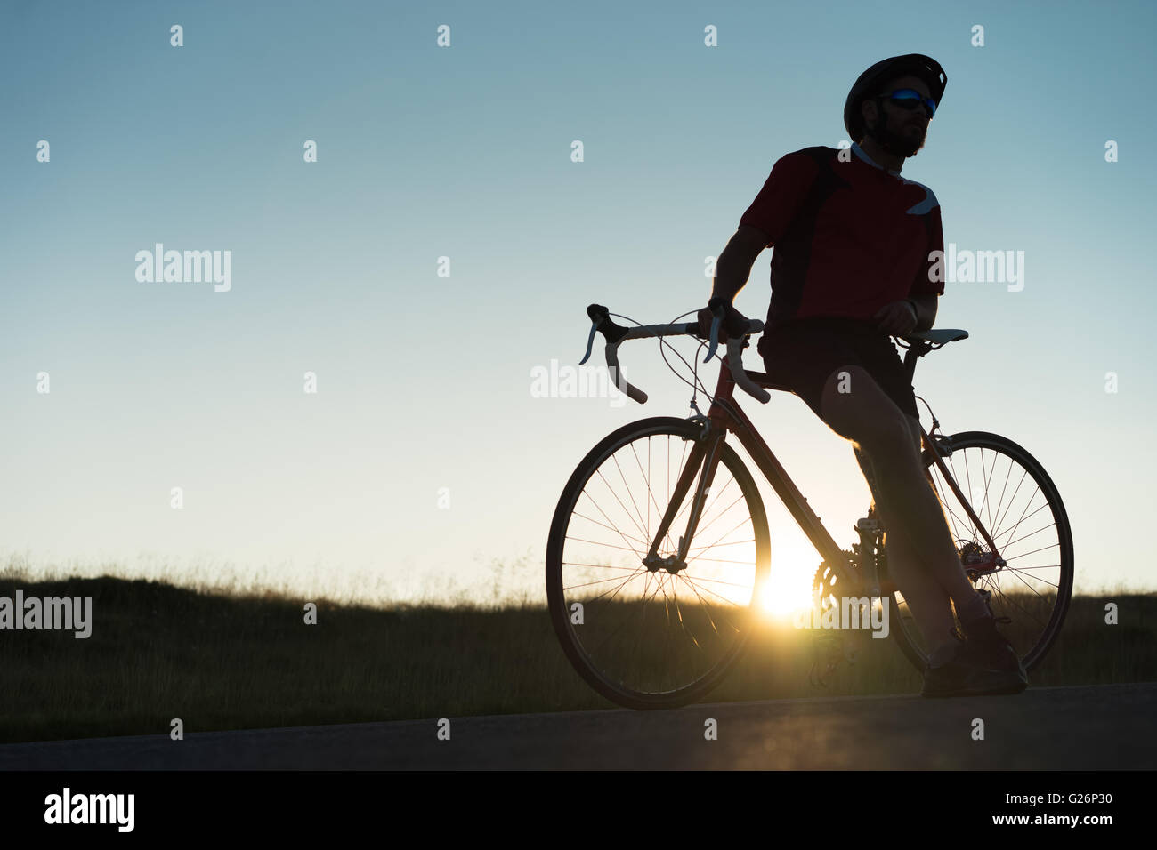 cyclist reclining against his road bike at sunset Stock Photo - Alamy