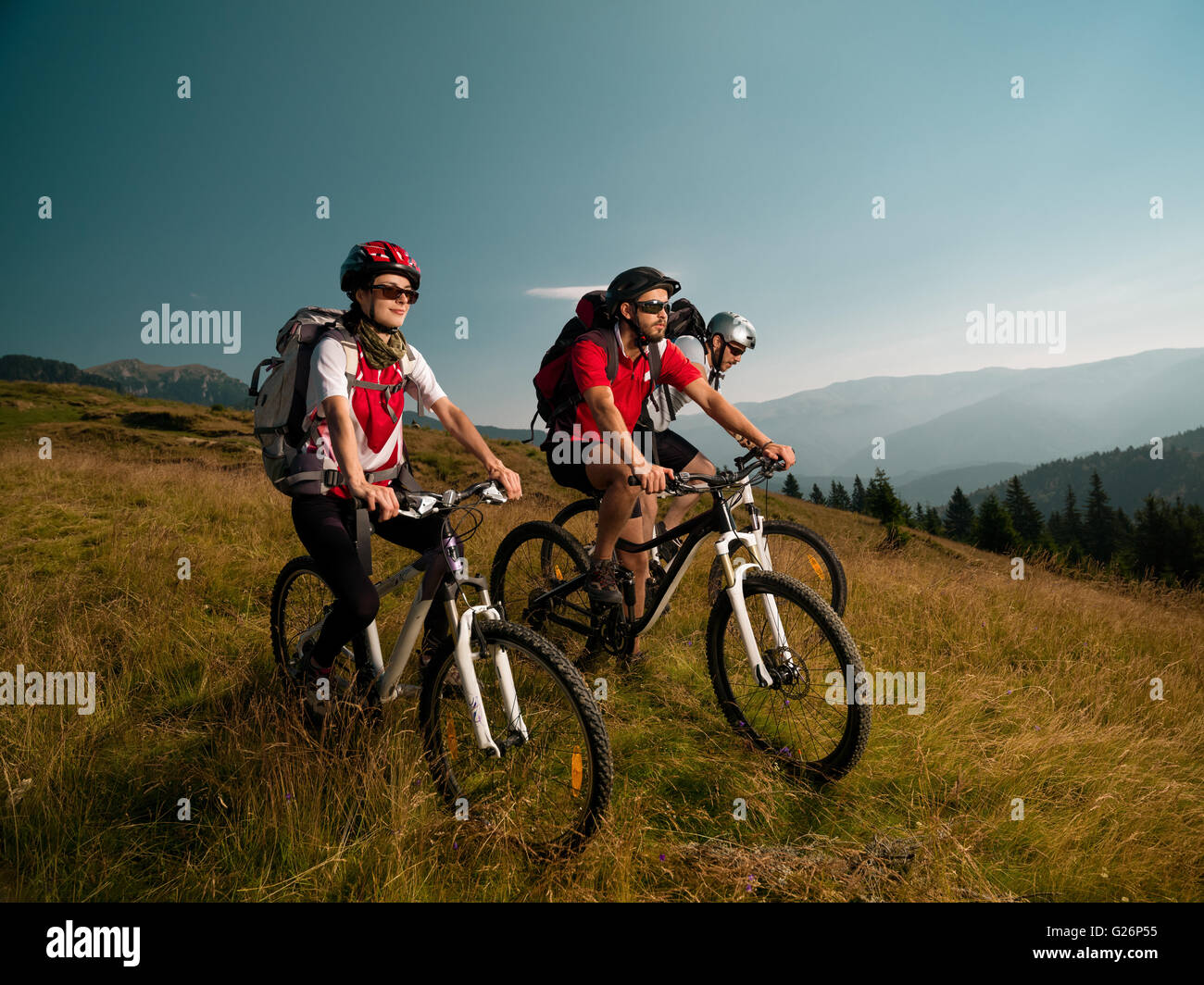 mountain bikers on a meadow, looking forward attentively at the ...