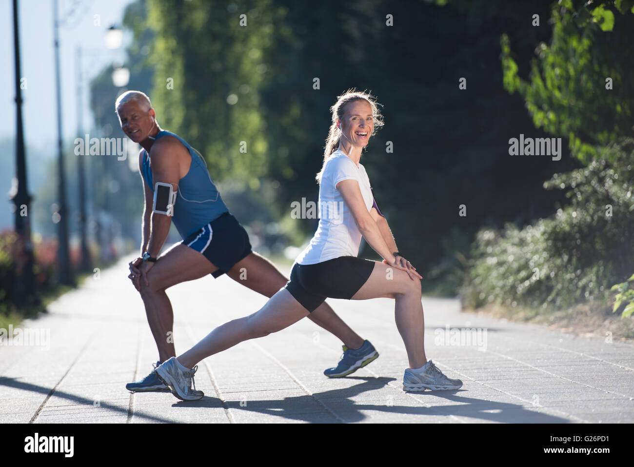 jogging couple warming up and stretching before morning running ...