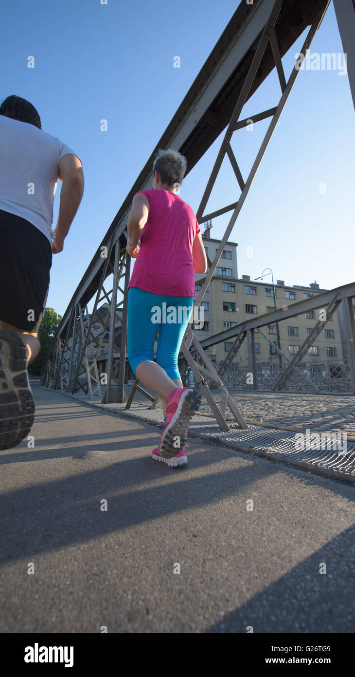 healthy mature couple jogging in the city at early morning with sunrise ...
