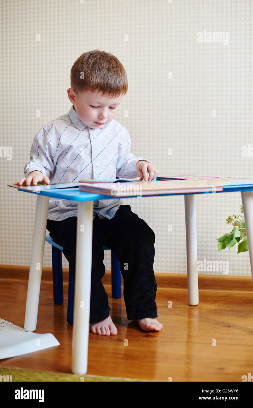 little boy sitting at the desk and reading a book Stock Photo - Alamy
