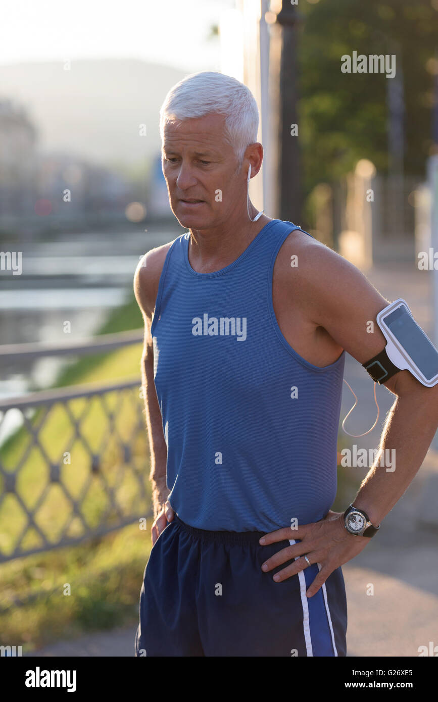 portrait of handsome senior jogging man while relaxing and take break ...
