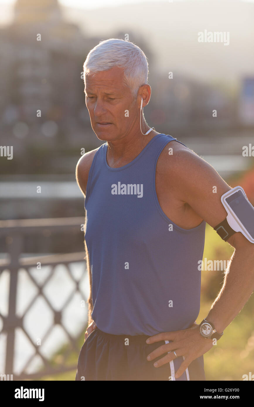 portrait of handsome senior jogging man while relaxing and take break ...