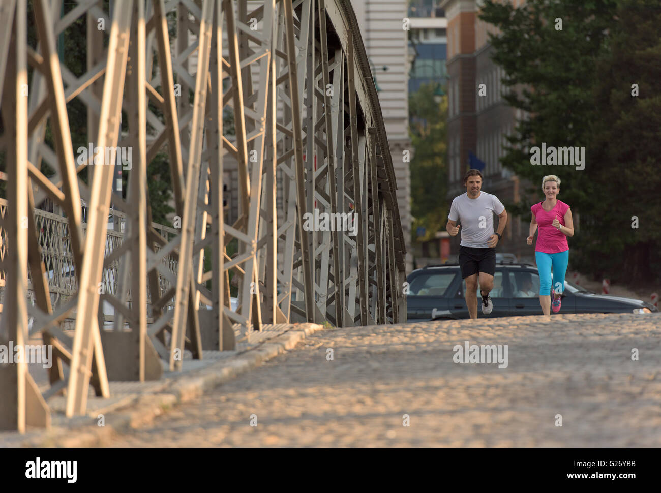 healthy mature couple jogging in the city at early morning with sunrise ...