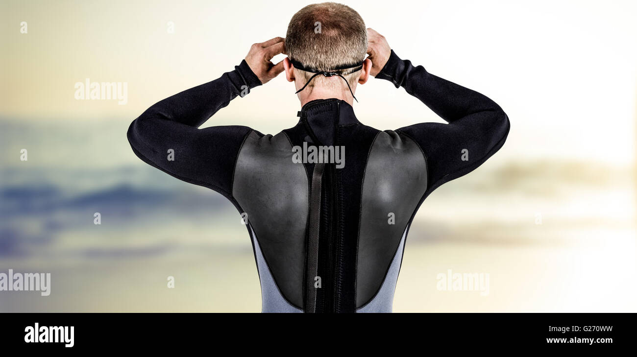 Composite image of rear view of swimmer in wetsuit wearing swimming ...