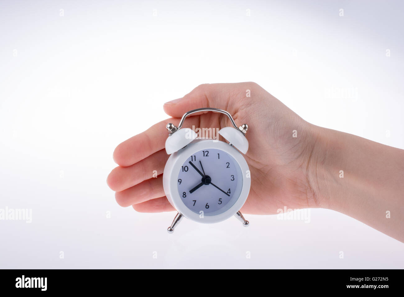 Alarm clock in hand on a white background Stock Photo - Alamy