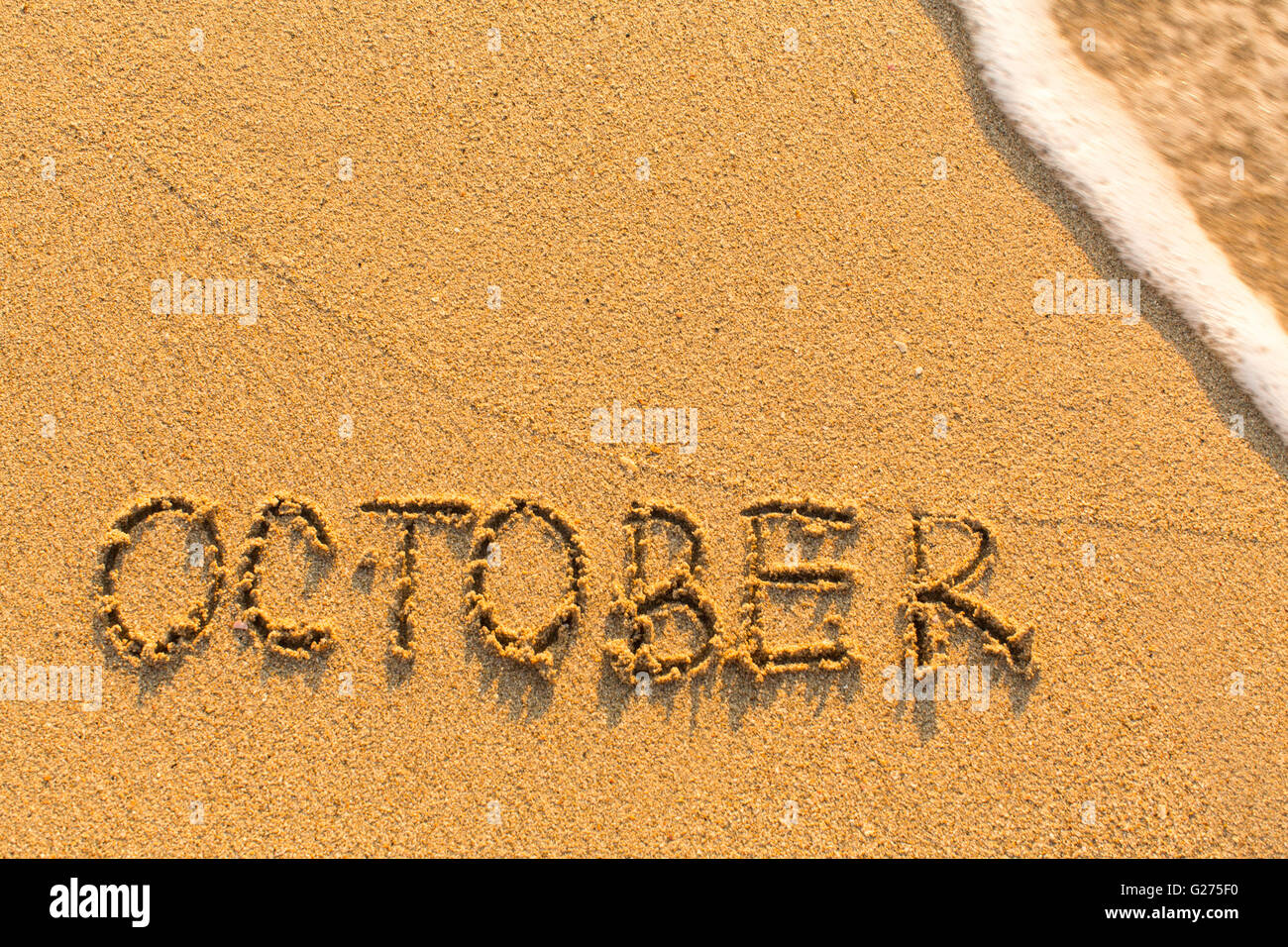 October - written by hand on a golden beach sand Stock Photo - Alamy