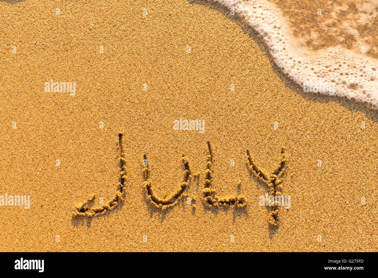 July - written by hand on a golden beach sand Stock Photo - Alamy