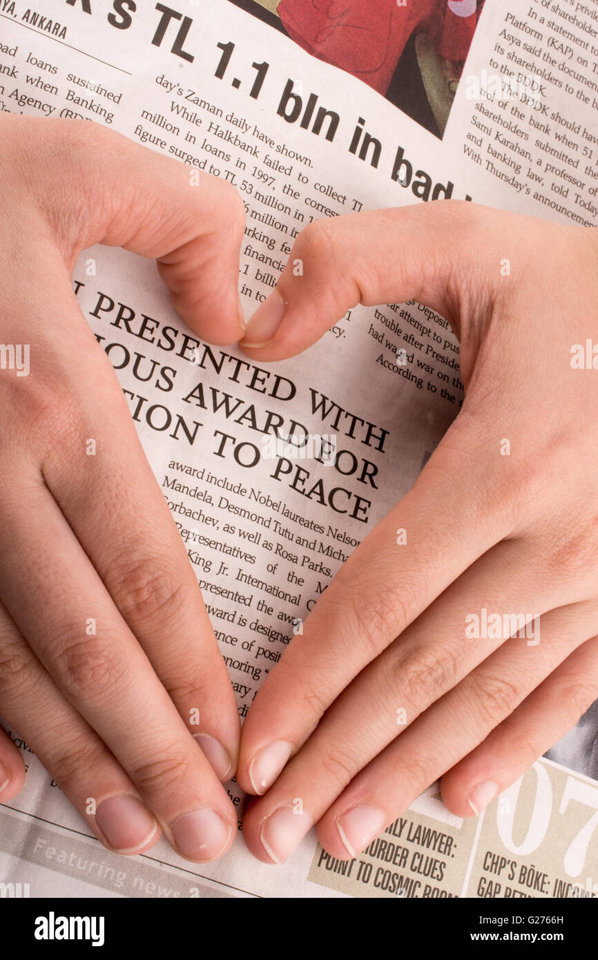 Hand making a heart shape on a newspaper Stock Photo - Alamy