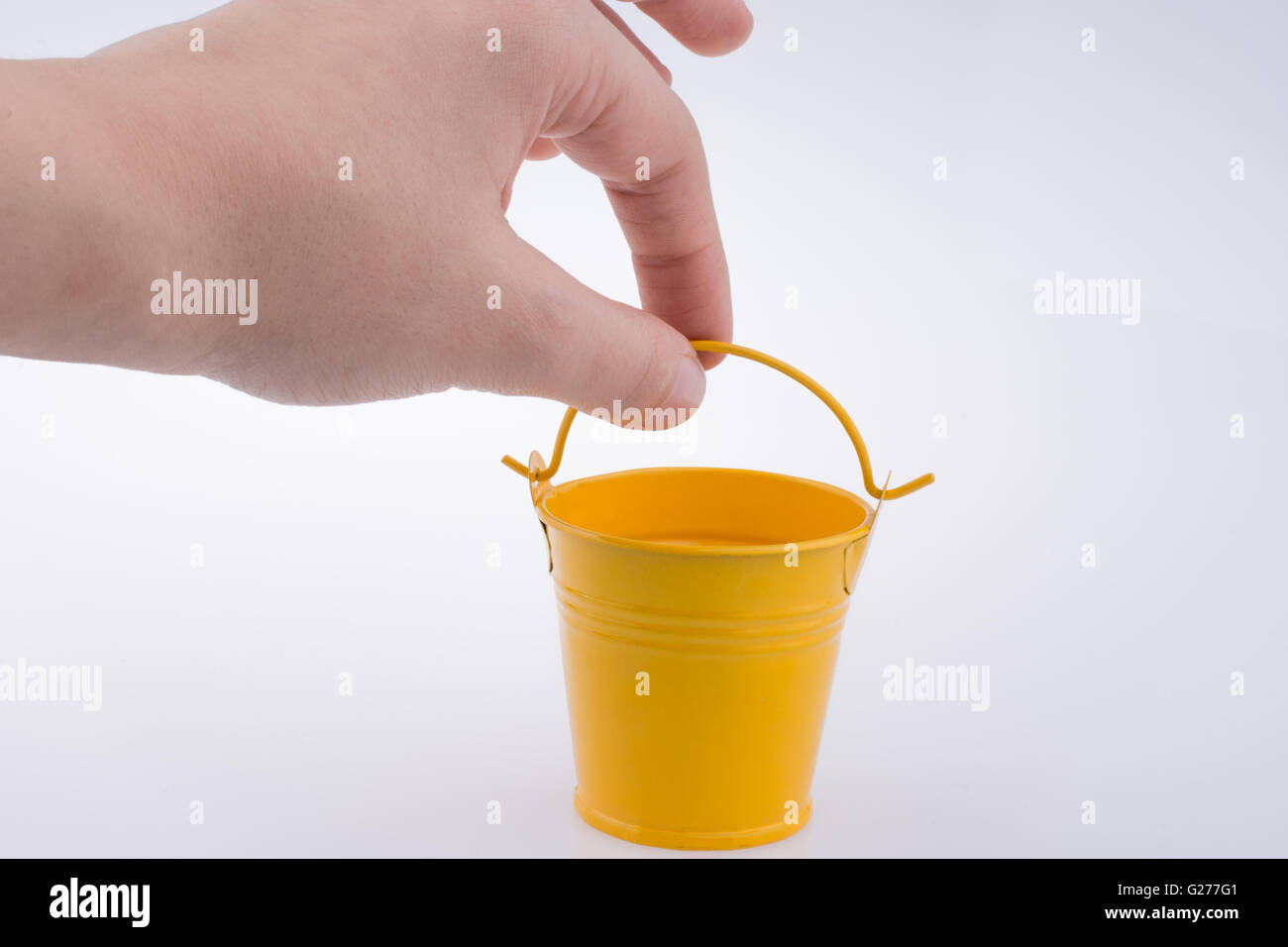 Hand holding a yellow bucket on a white background Stock Photo - Alamy