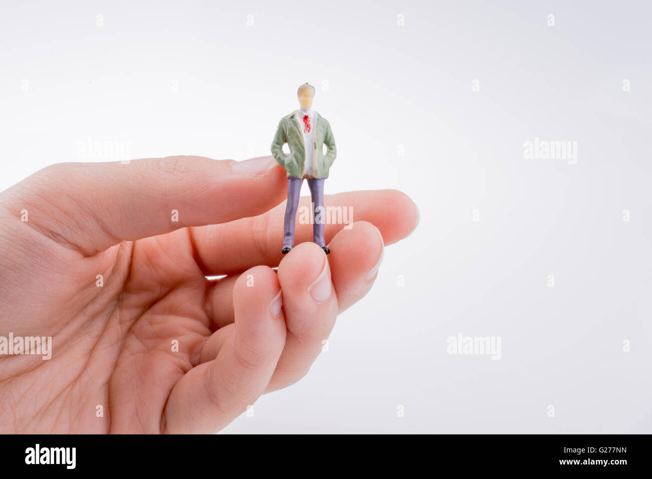Hand holding a human figure on a white background Stock Photo - Alamy