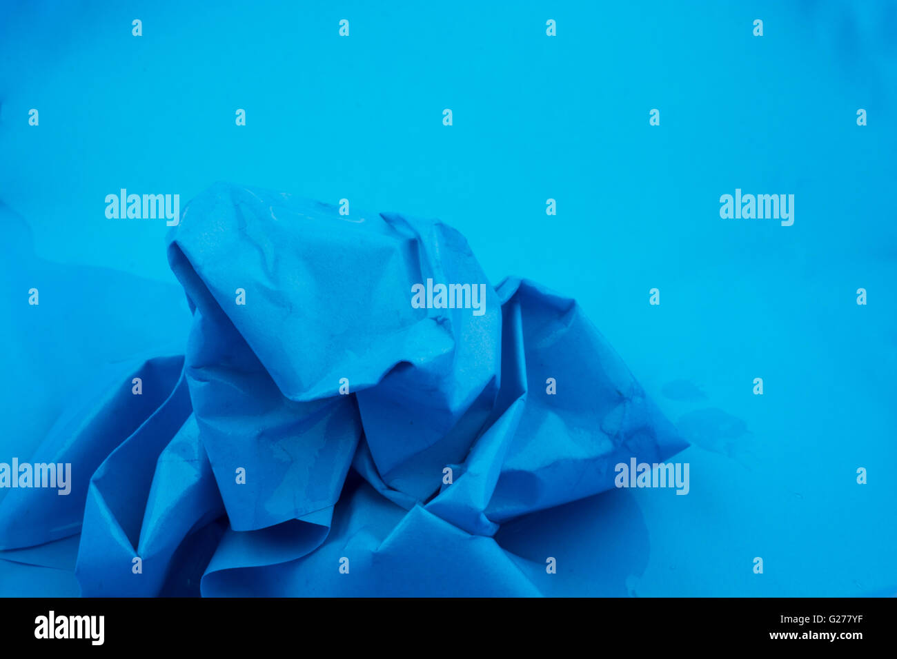 Crumpled paper put in water in blue background Stock Photo - Alamy