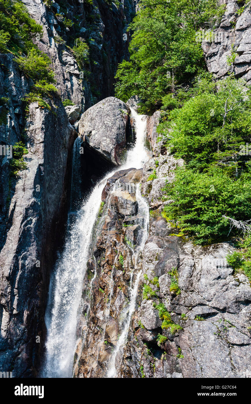 Mountain waterfall flowing and splashing down rocky cliffs among a few ...