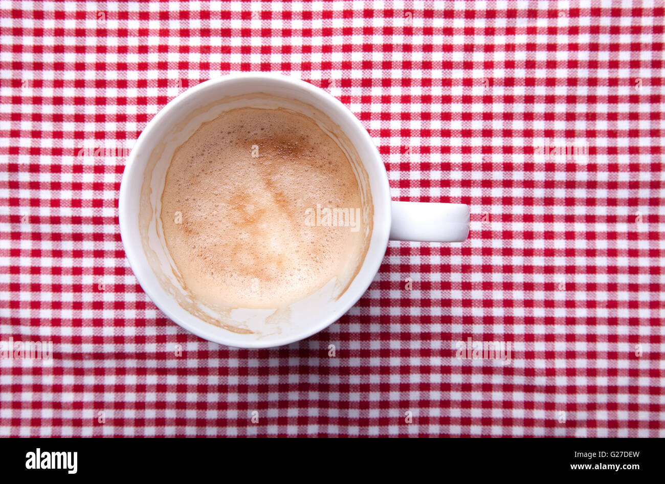 Almost empty coffee cup on chequered cloth Stock Photo - Alamy