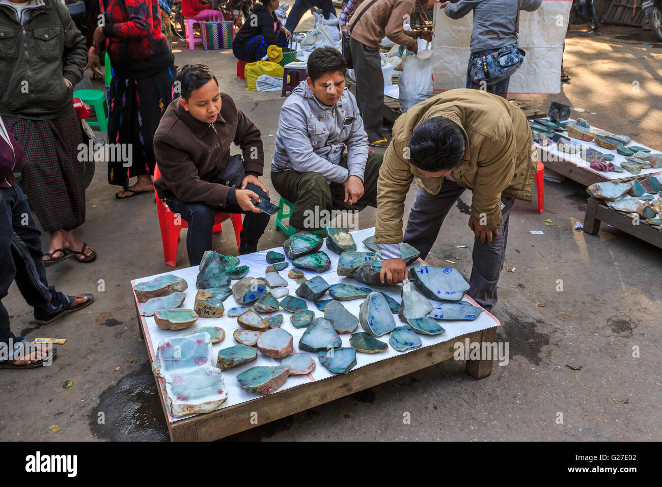 Buyer inspects large pieces of cut and polished jade on sale at the ...