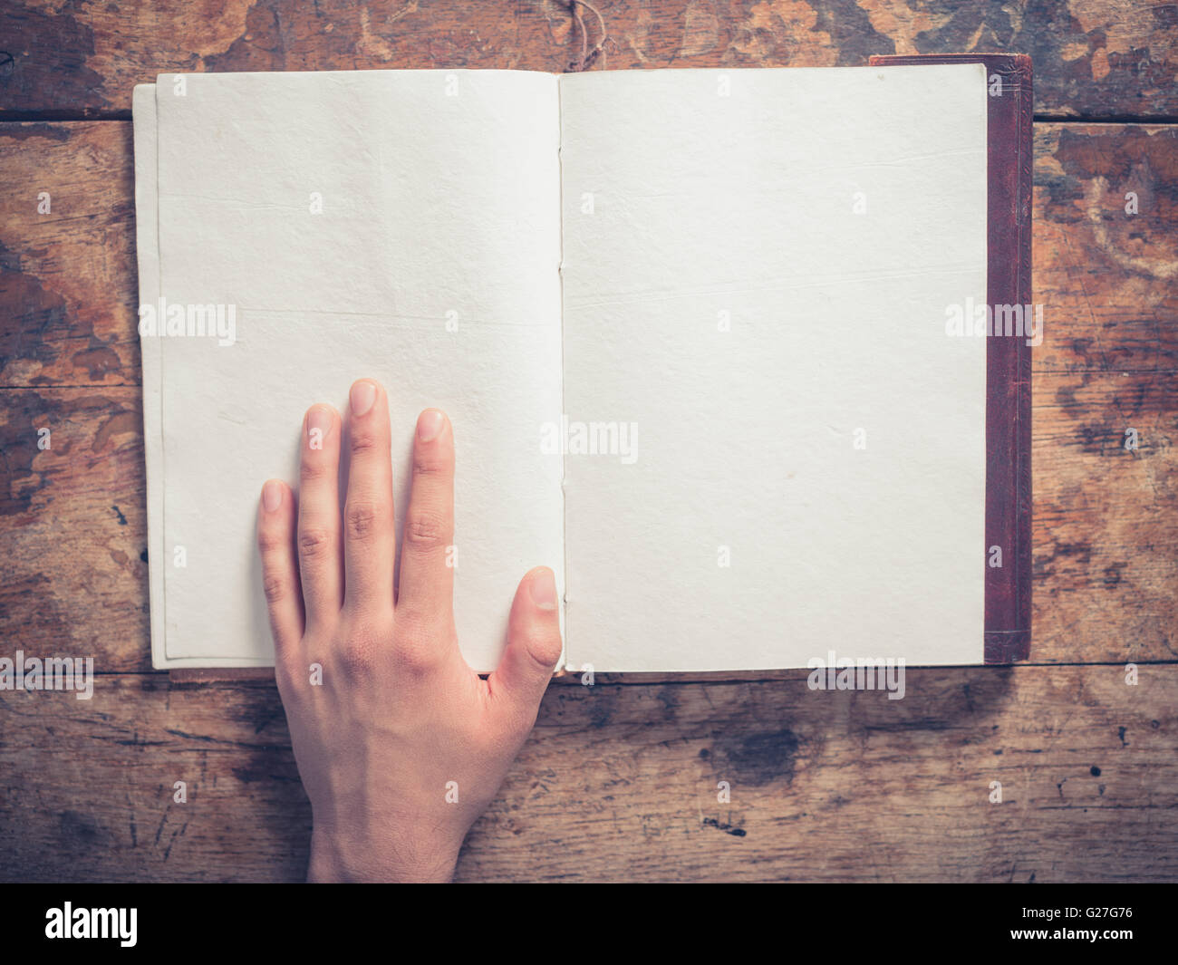 A male hand and a big notepad on a wooden table Stock Photo - Alamy