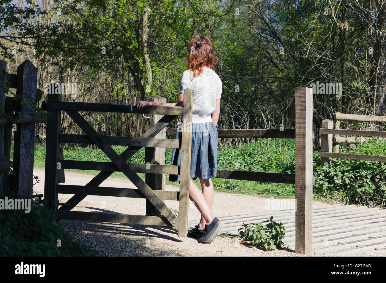 A young woman is standing by a wooden gate in a forest Stock Photo - Alamy