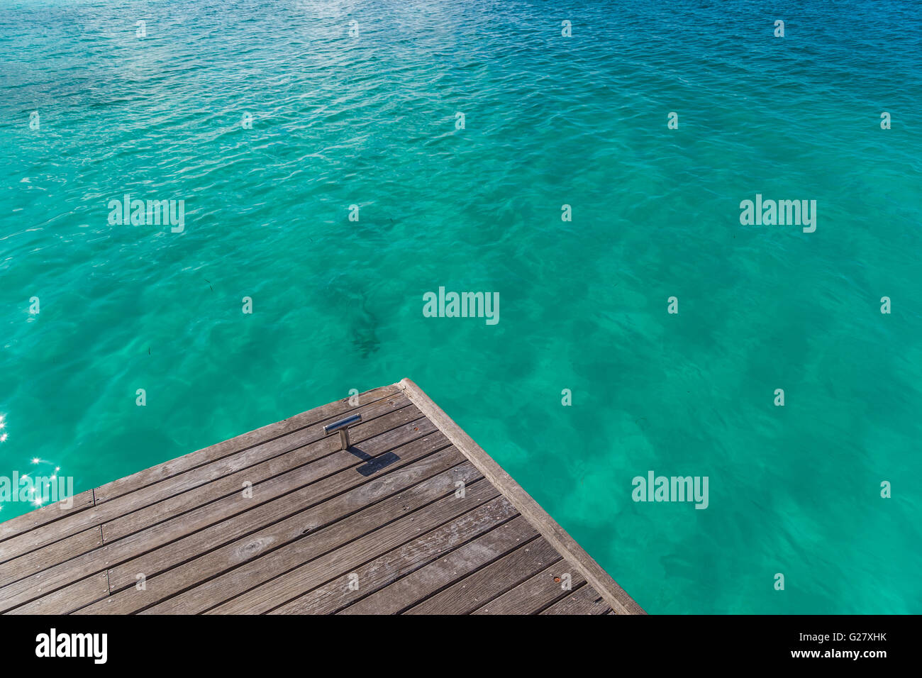 Jetty to a tropical beach. Edge of the water, jetty and the blue lagoon ...
