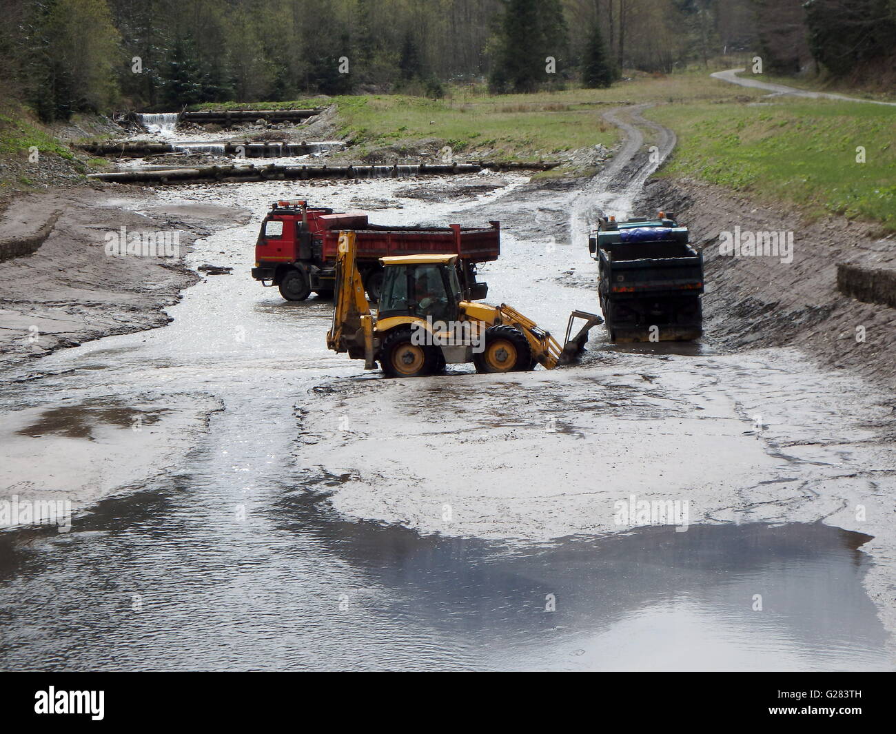 yellow wheel loaders and trucks in the mud Stock Photo - Alamy