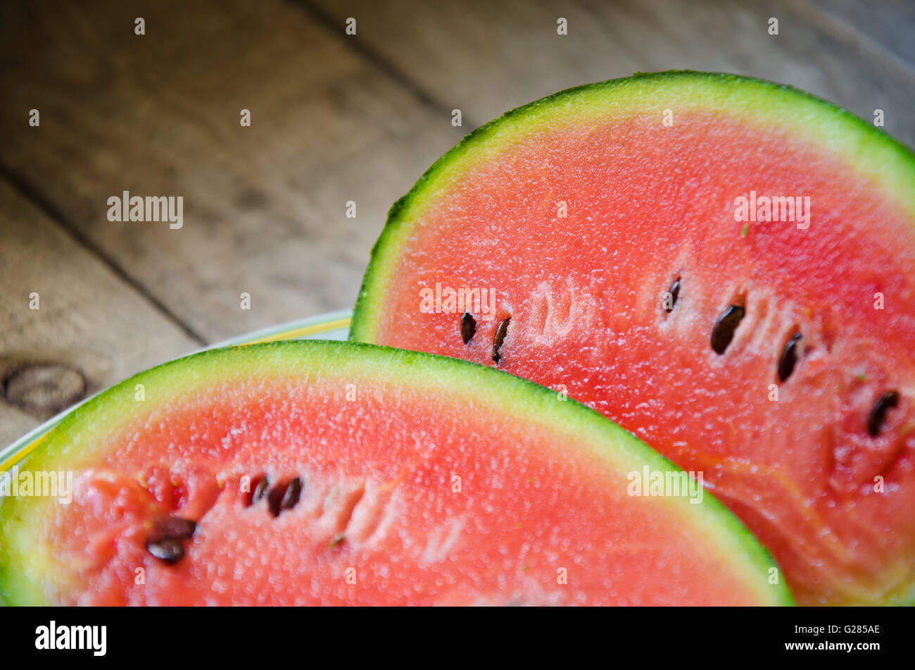 Freshly slices of pink watermelon on a plate on a palet wood surface ...