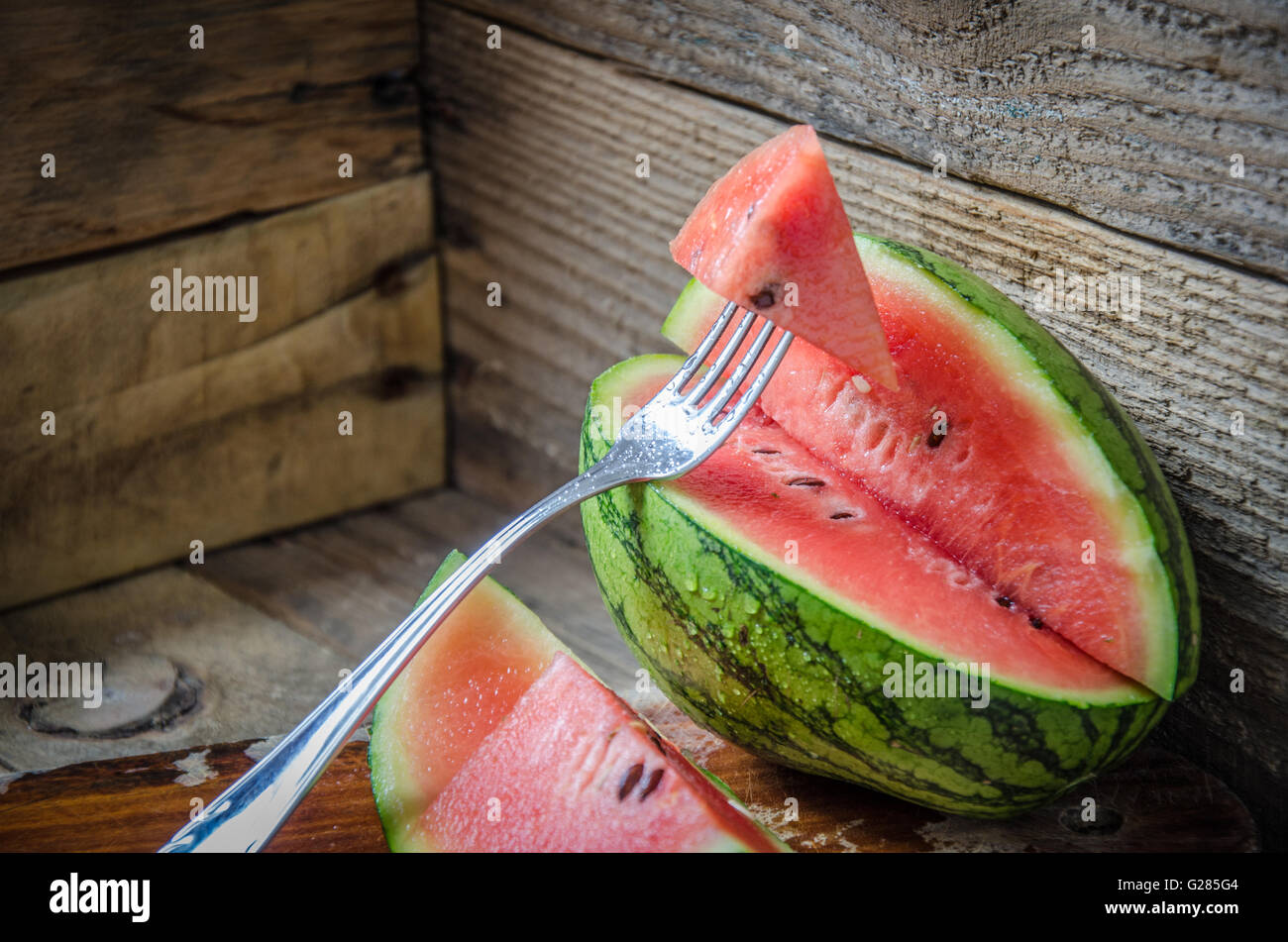 Freshly slices of pink watermelon on a plate on a palet wood surface ...