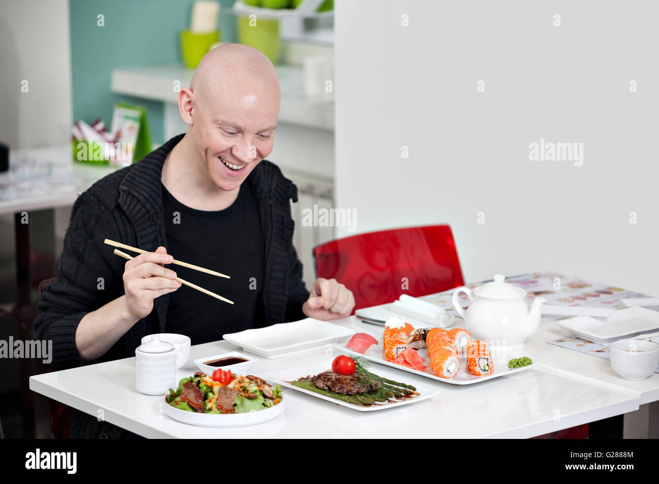 Young man sitting at sushi bar, smiling Stock Photo - Alamy