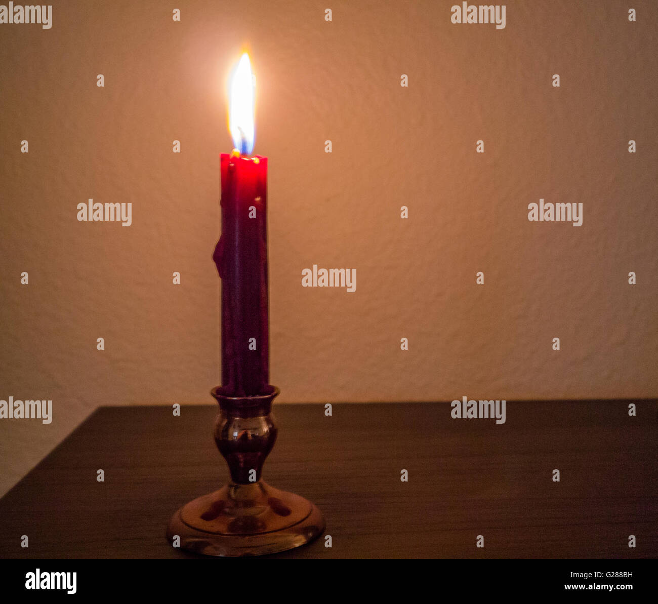 Single copper candlestick with red, lit taper Stock Photo - Alamy