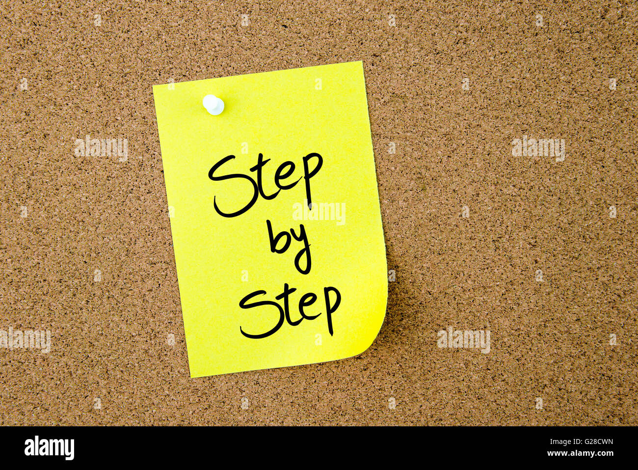 Step By Step written on yellow paper note pinned on cork board with ...
