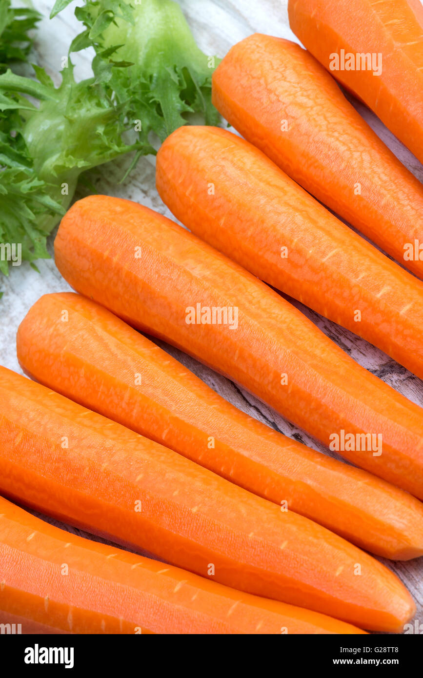 Raw peeled carrots and lettuce on a wooden table Stock Photo - Alamy
