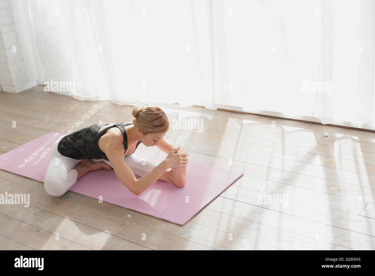 Attractive young Japanese practicing yoga in an airy room Stock Photo ...